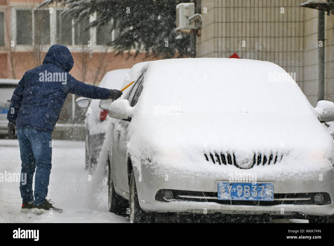 --FILE--A taxi driver clears snow off his car after a snow in Yantai ...