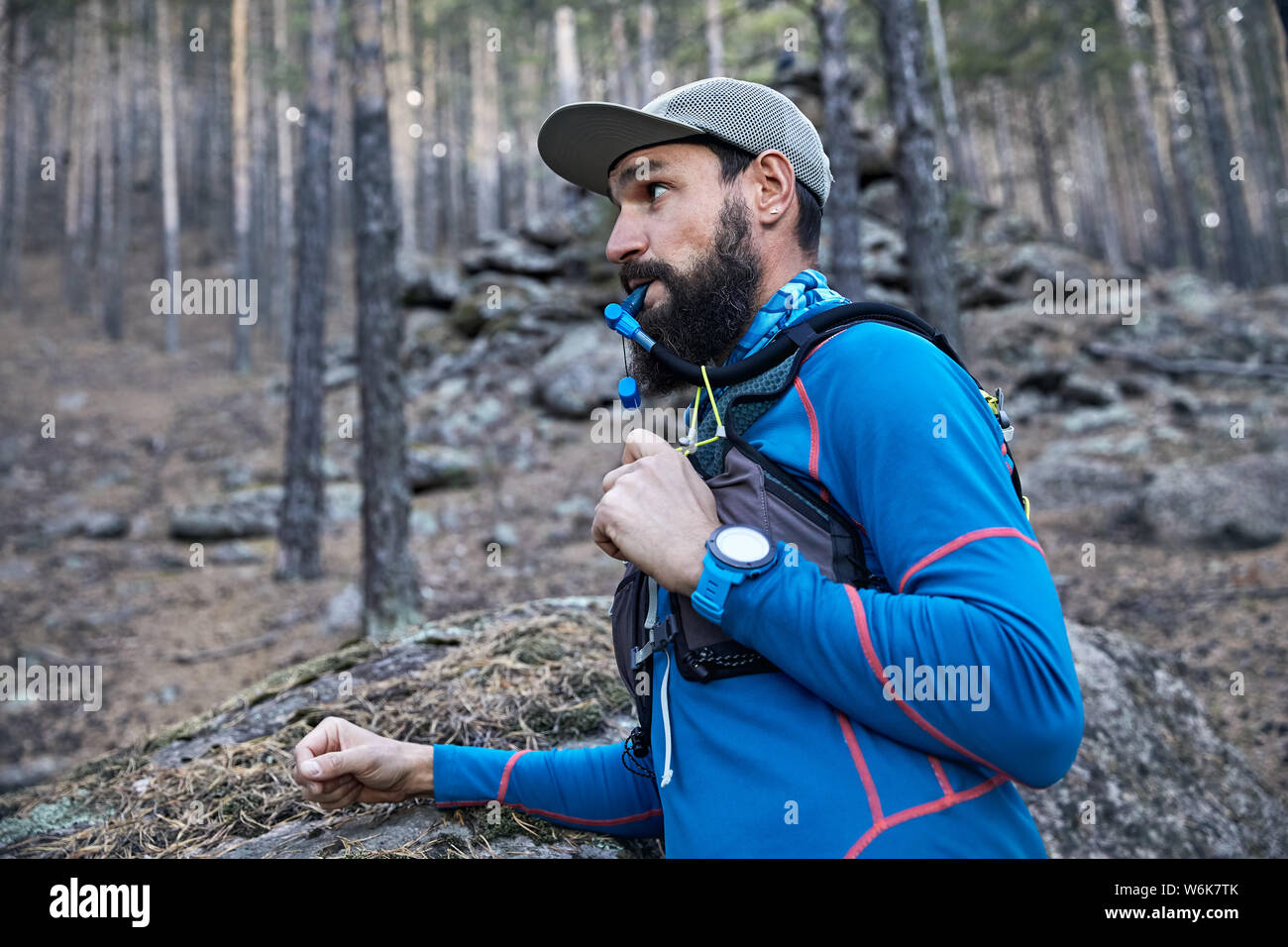 Portrait of runner athlete with beard drinking water from the tube of ...