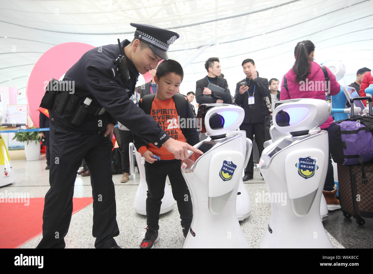 A police officer helps a child interact with one of the automated ...