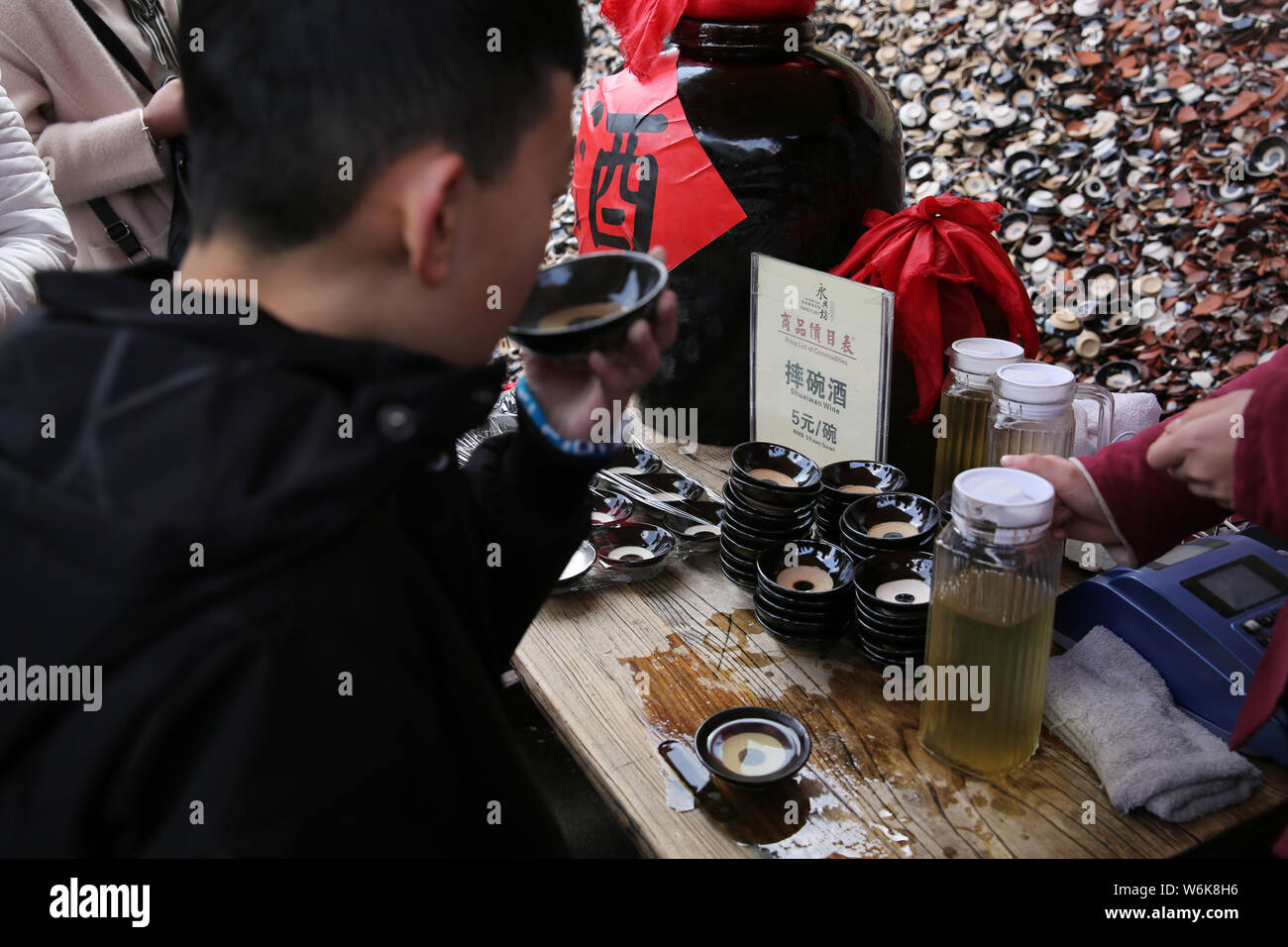 A tourist drinks a bowl of rice wine during the Chinese Lunar New Year ...