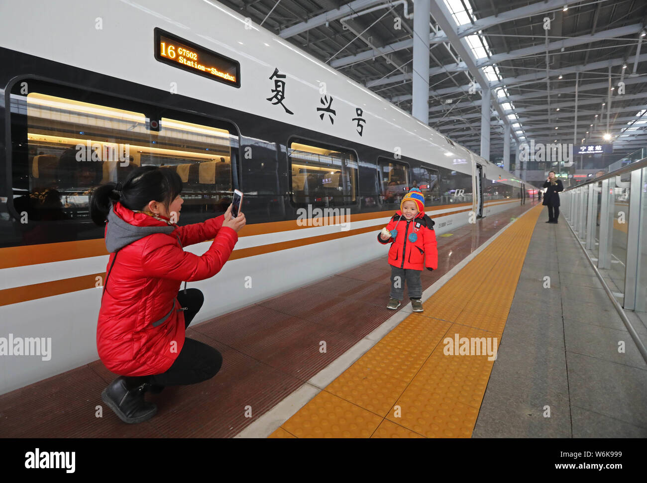 Passengers pose for photos with a "Fuxing" high speed bullet train at ...