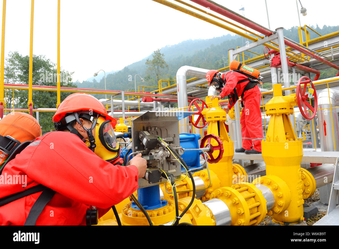 Chinese technicians examine pipes at a natural gas purification plant ...