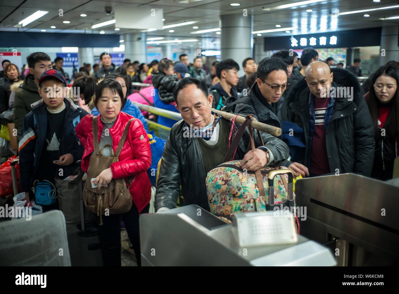 Chinese passengers queue up to have their train tickets scanned for ...