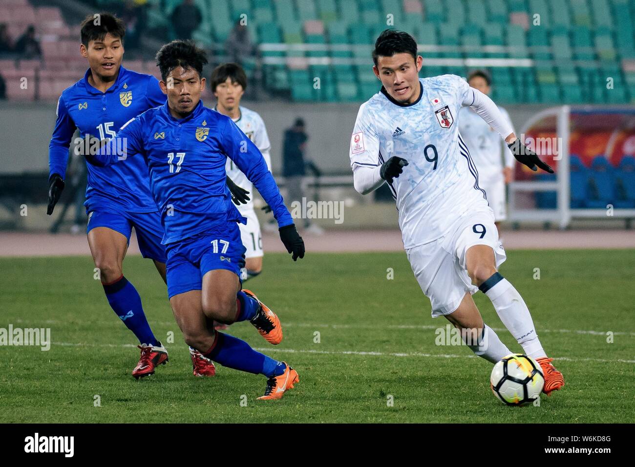 Kyosuke Tagawa, right, of Japan kicks the ball to make a pass against players of Thailand in ...
