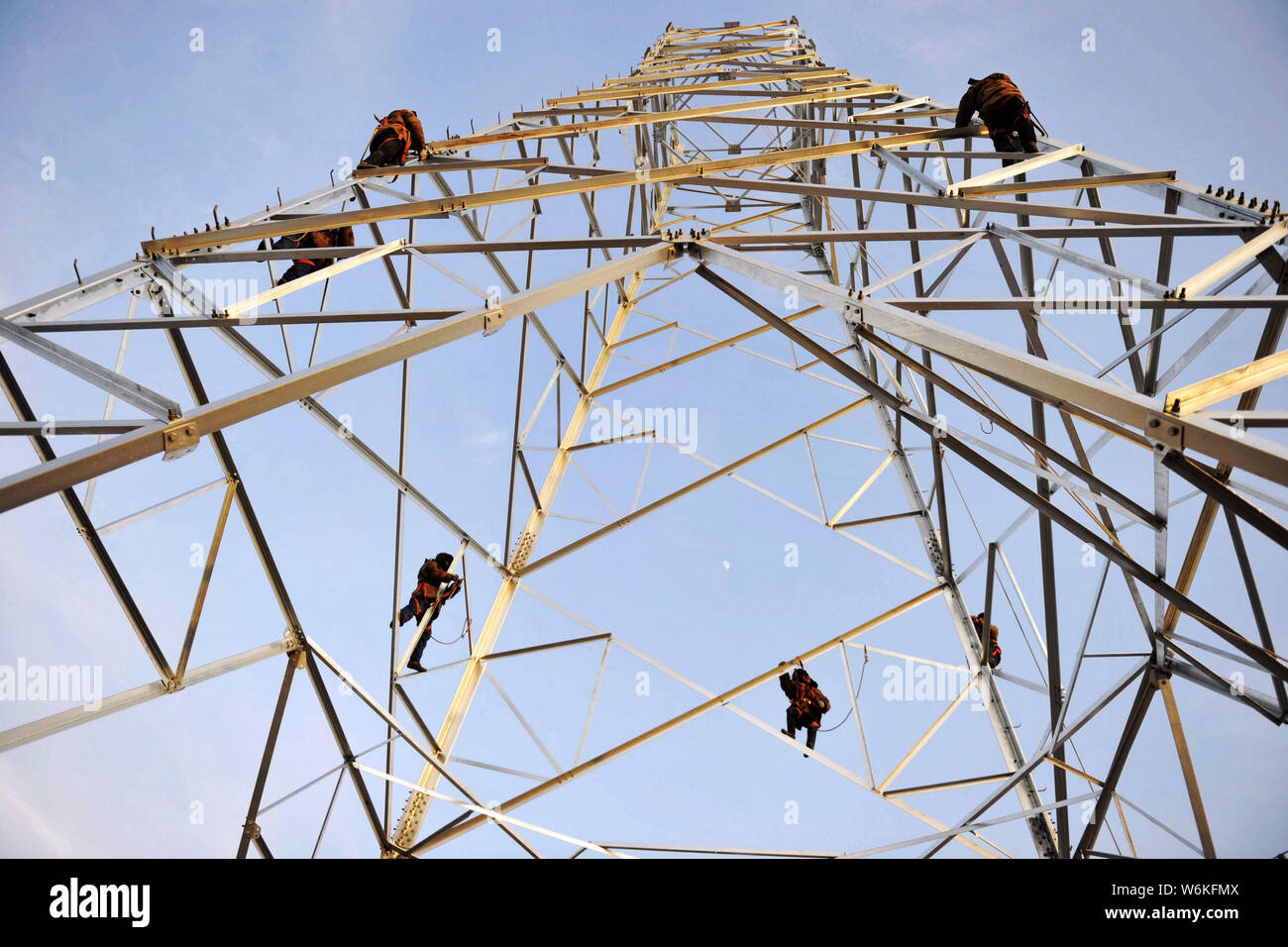 Chinese workers install a electricity pylon in freezing temperatures ...