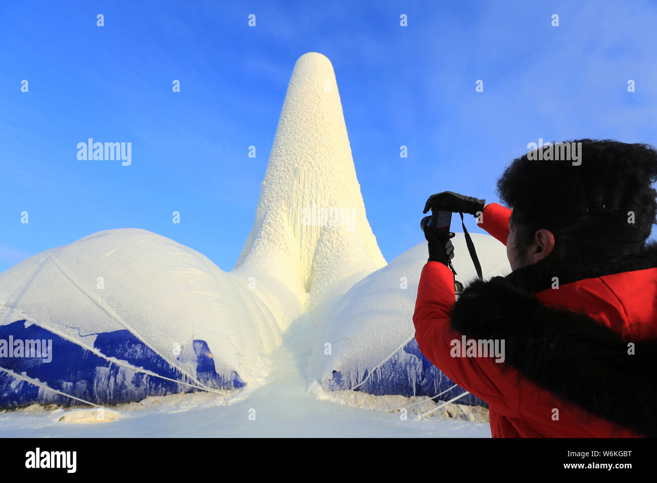 A tourist takes photos of the world's tallest ice tower, which is 30 ...