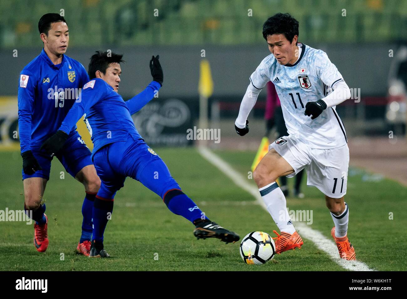 Keita Endo, right, of Japan kicks the ball to make a pass against players of Thailand in their ...