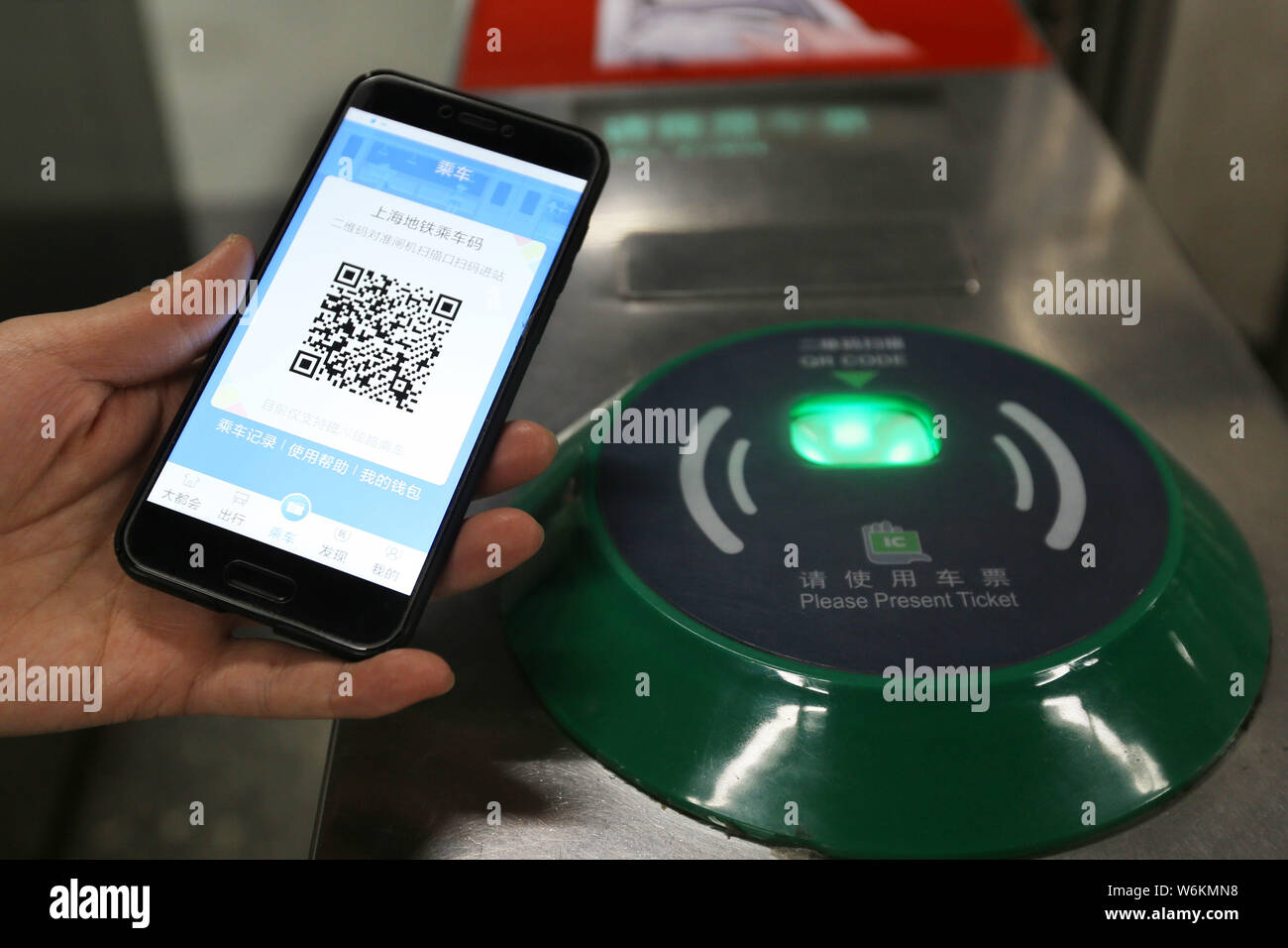 A passenger puts her smartphone above a turnstile to have the QR code ...