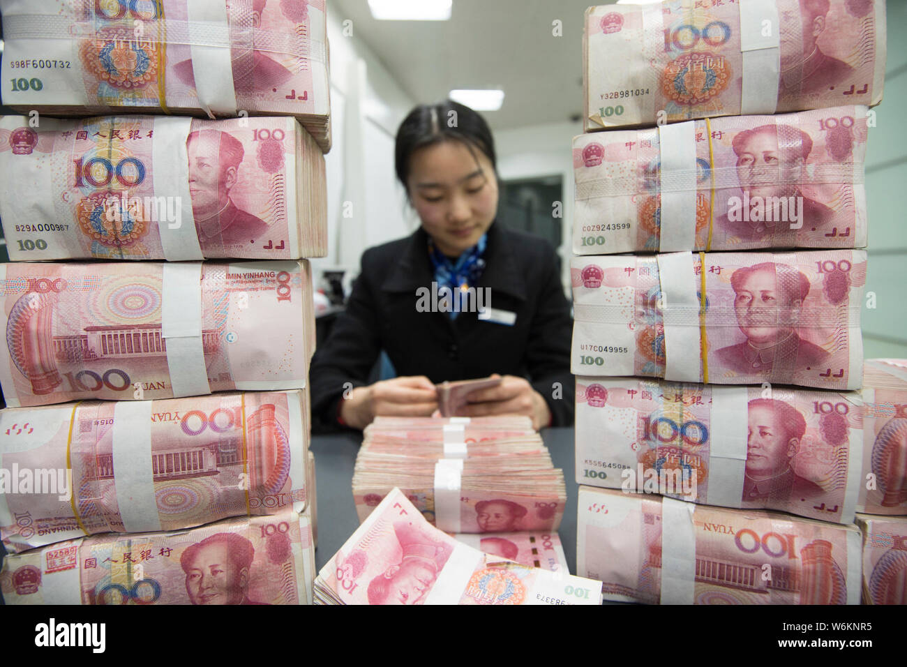 A Chinese clerk counts RMB (renminbi) yuan banknotes at a bank in Haian ...