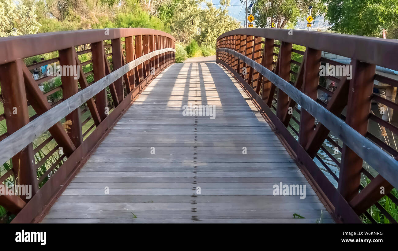 frame Bridge with wood deck and rusty metal railing over a lake with ...