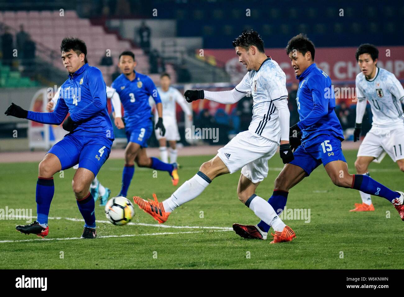 Kyosuke Tagawa, center, of Japan kicks the ball to make a pass against players of Thailand in ...