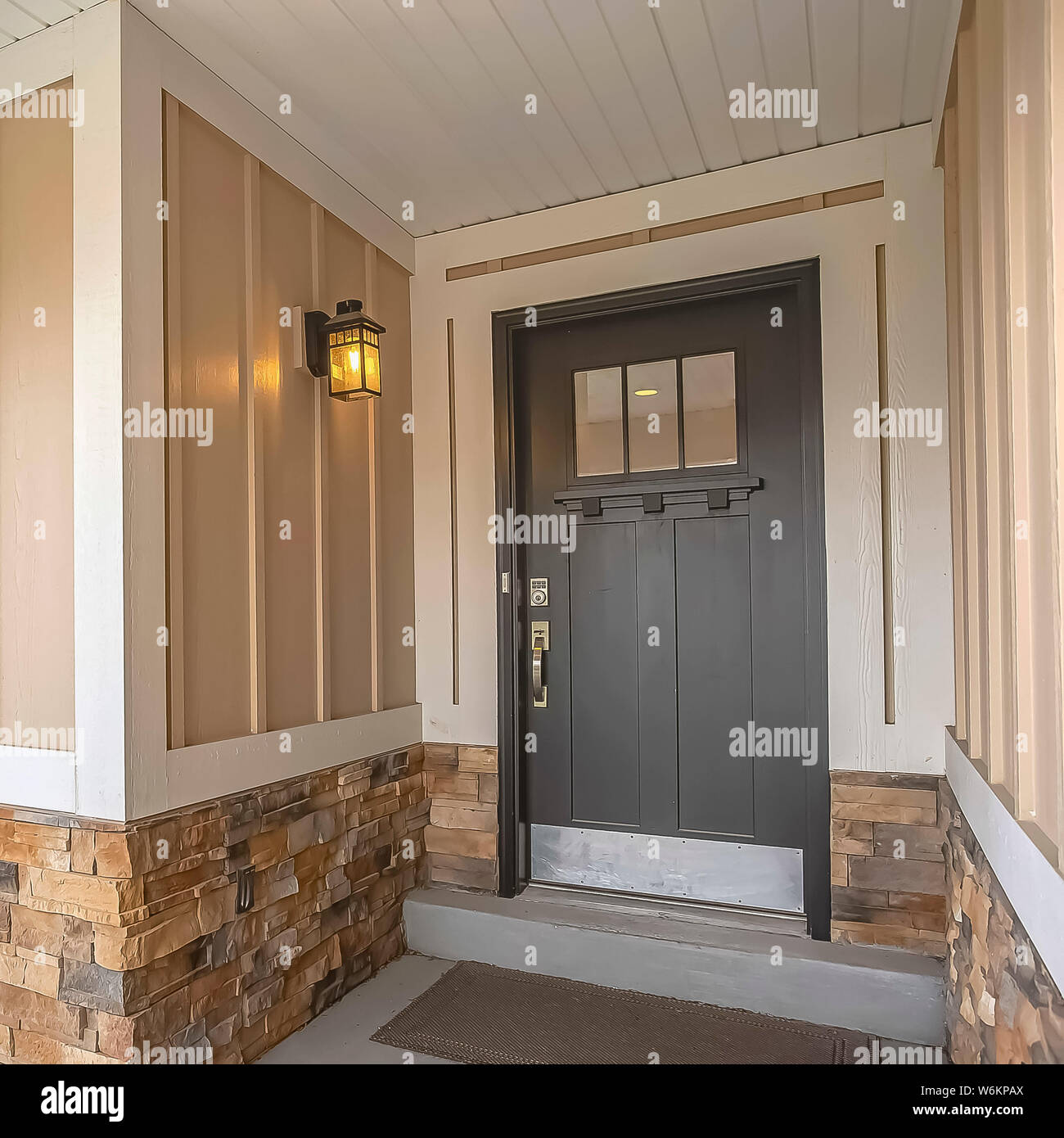 Square Home facade with a glass paned front door and stone brick and ...