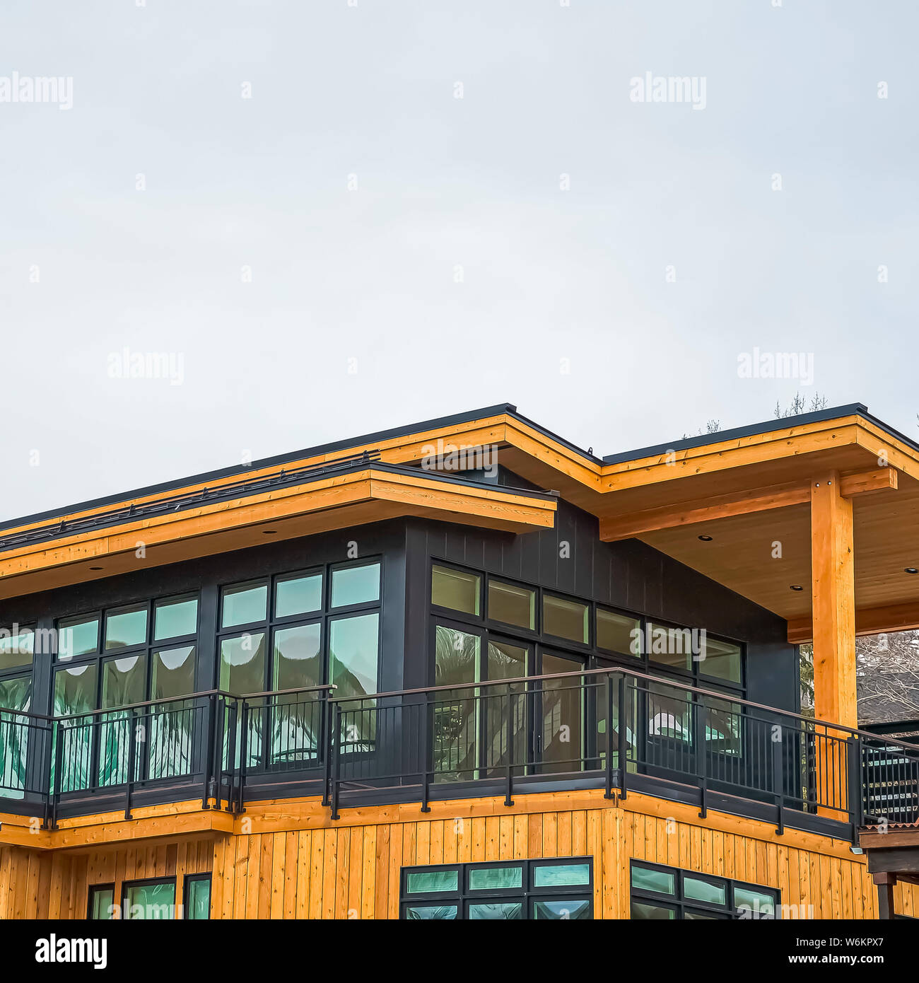 Square Exterior of a home with balcony shiny windows and gray and brown ...