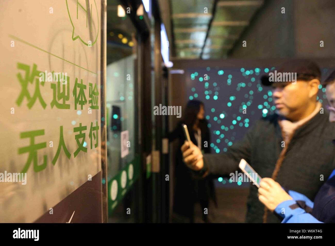 Customers use their smartphones to scan a QR code with their WeChat app ...
