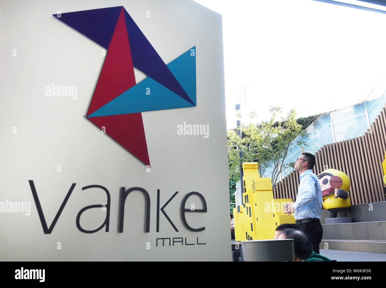 --FILE--A pedestrian walks past a logo of Vanke at the Vanke shopping ...