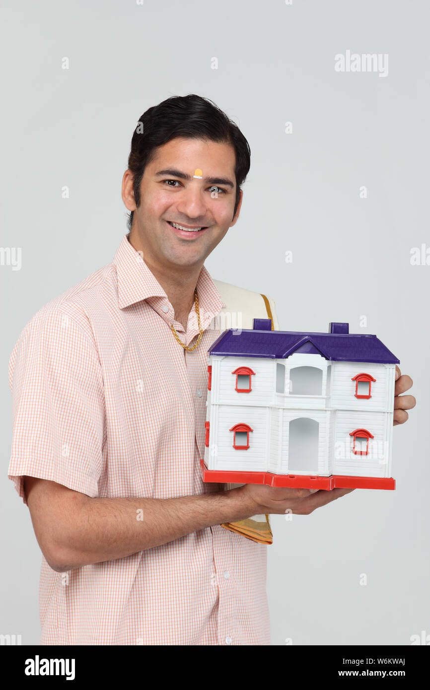 South Indian man holding a model of dream home and smiling Stock Photo ...