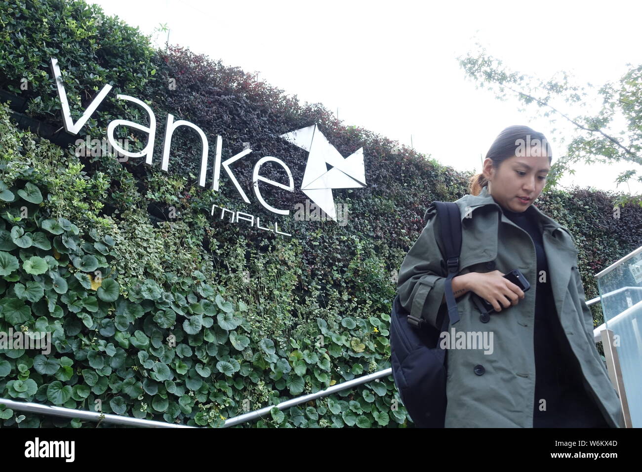--FILE--A pedestrian walks past a logo of Vanke at the Vanke shopping ...