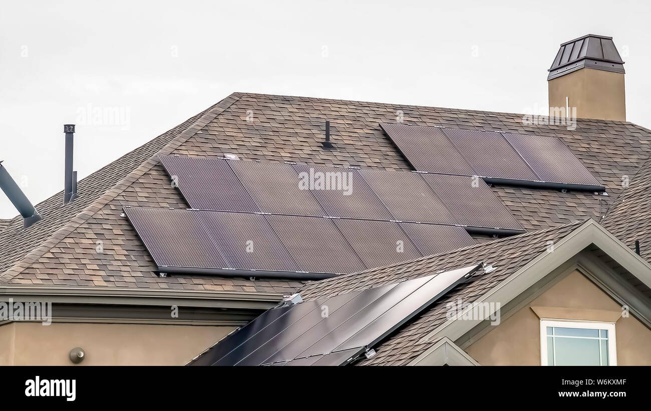 Panorama Solar panels on the dark pitched roof of a home with cloudy ...