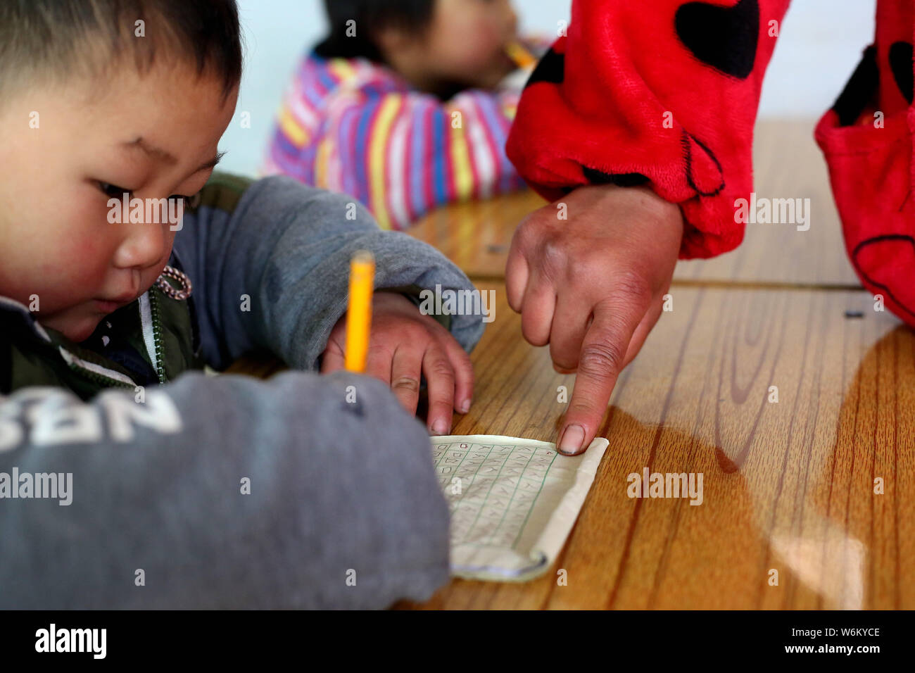 A primary student does homework in a classroom surrounded by dense ...