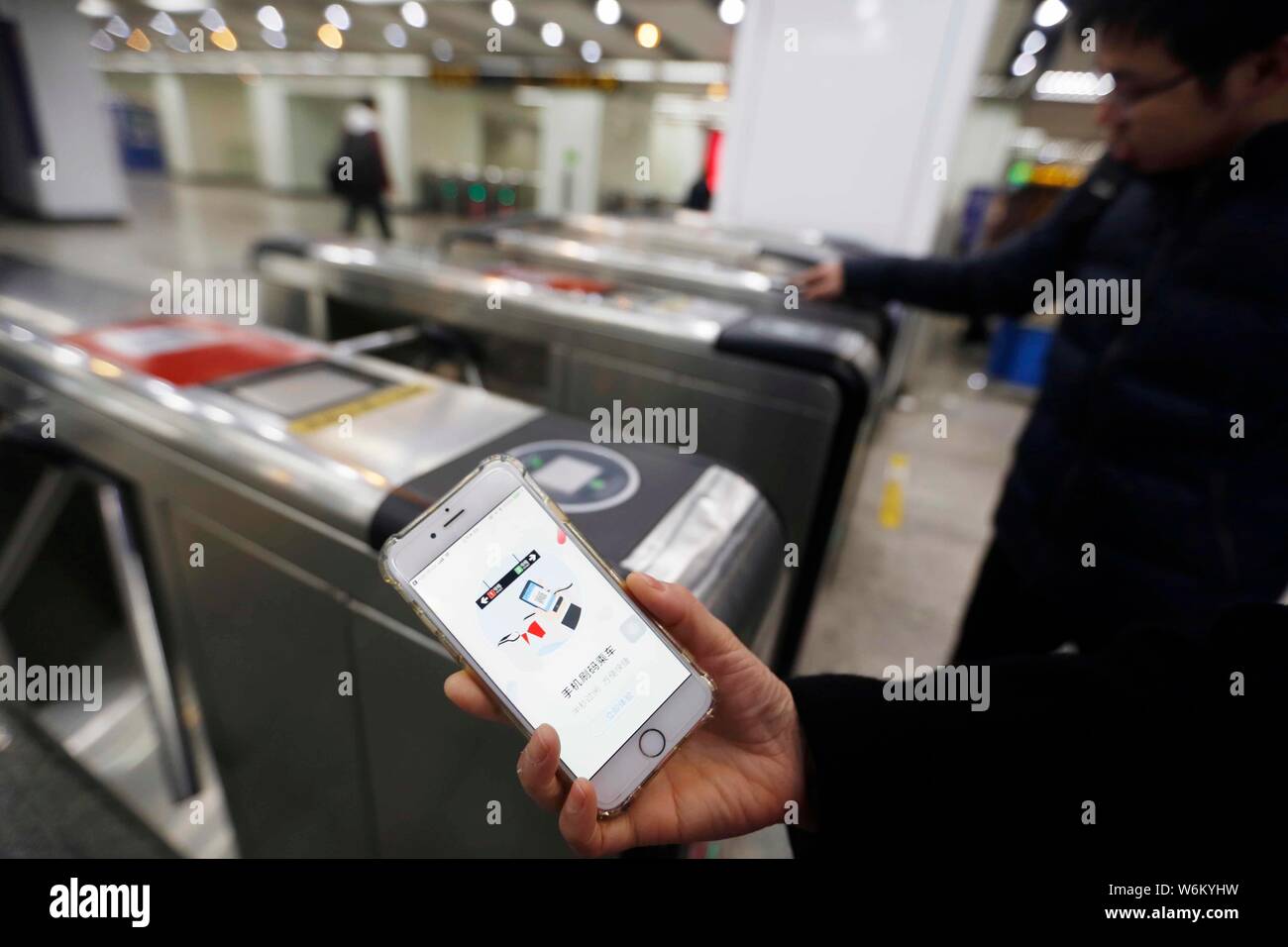 A passenger puts her smartphone above a turnstile to have the QR code ...