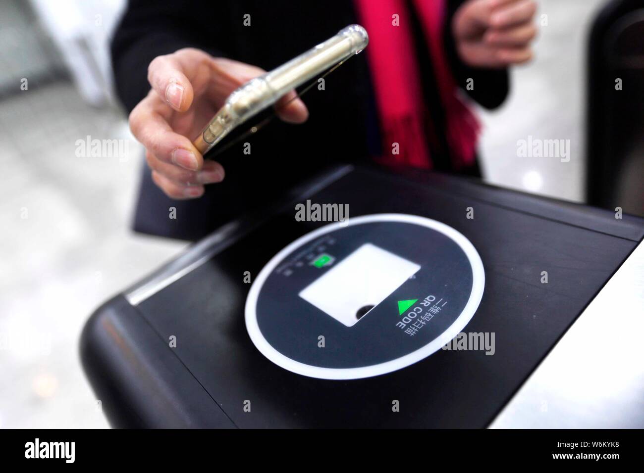 A passenger puts her smartphone above a turnstile to have the QR code ...