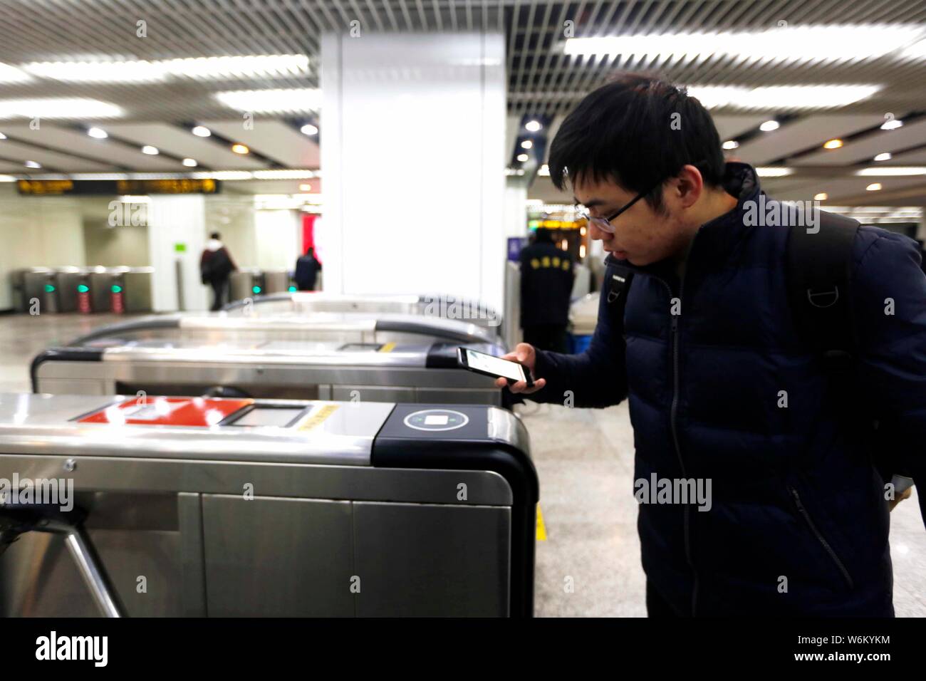 A passenger puts his smartphone above a turnstile to have the QR code ...