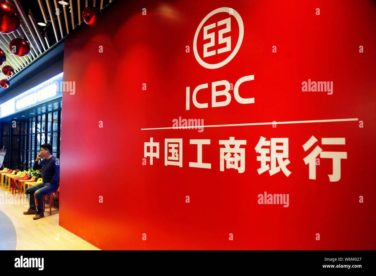 --FILE--A customer sits beside an advertisement for ICBC (Industrial ...