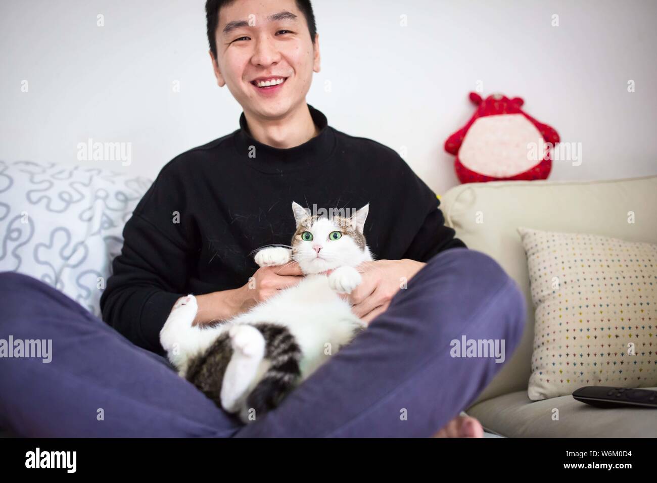 --FILE--A Chinese man is pictured with his cat at home in Guangzhou ...