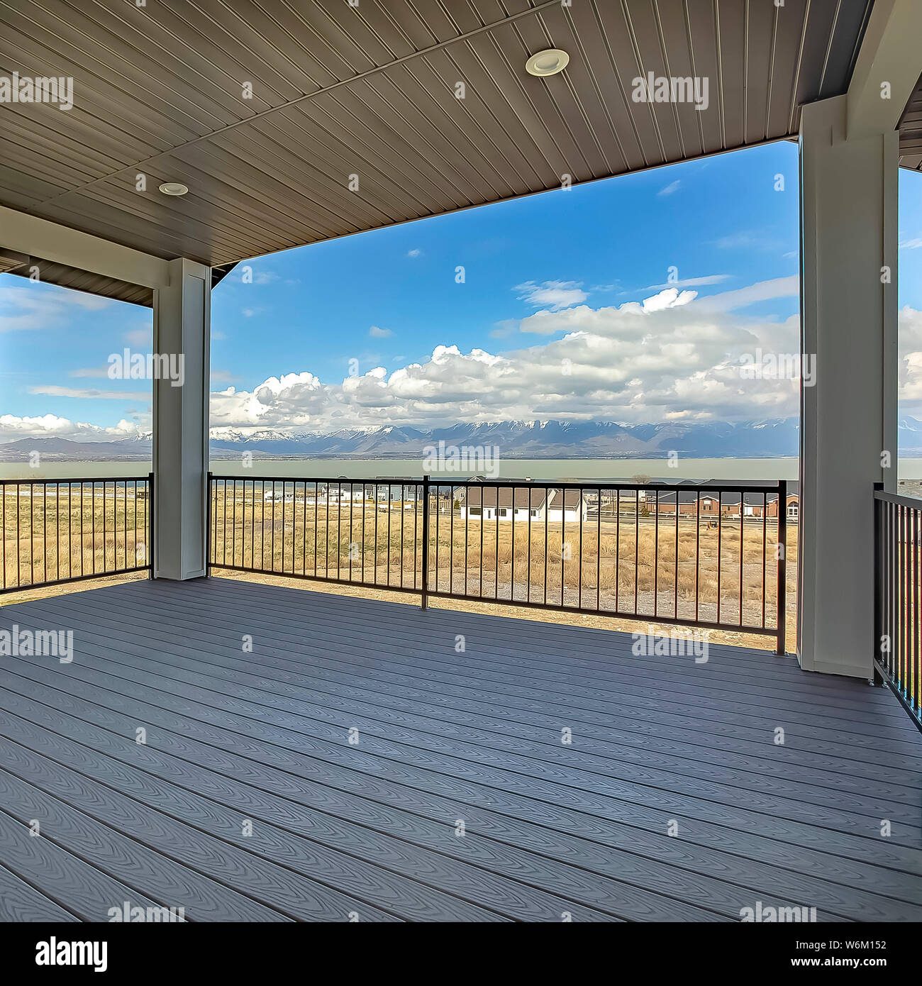Square Balcony with view of cloudy blue sky over homes lake and snow ...