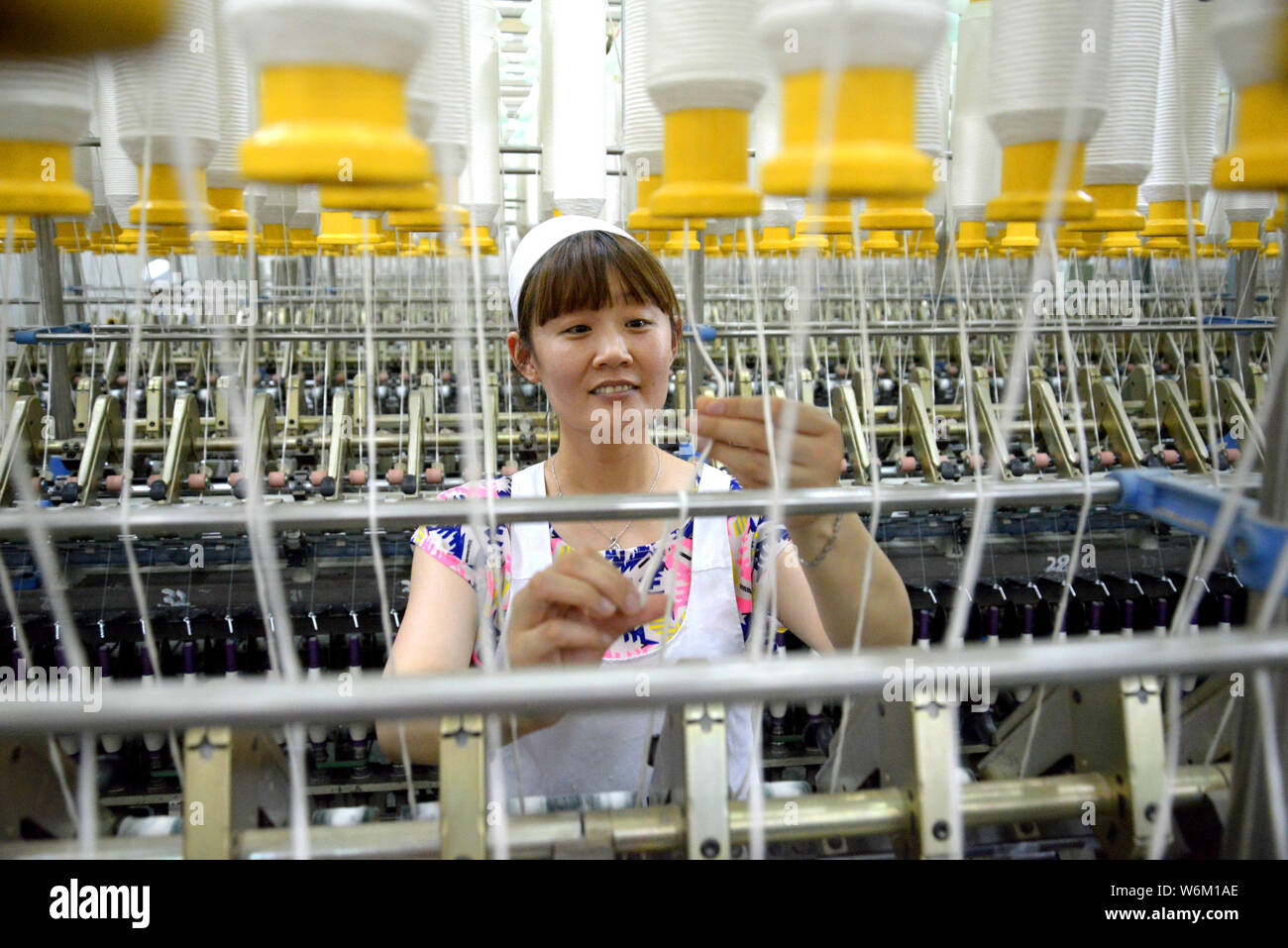 A female Chinese worker handles yarn spindles at a textile factory in ...