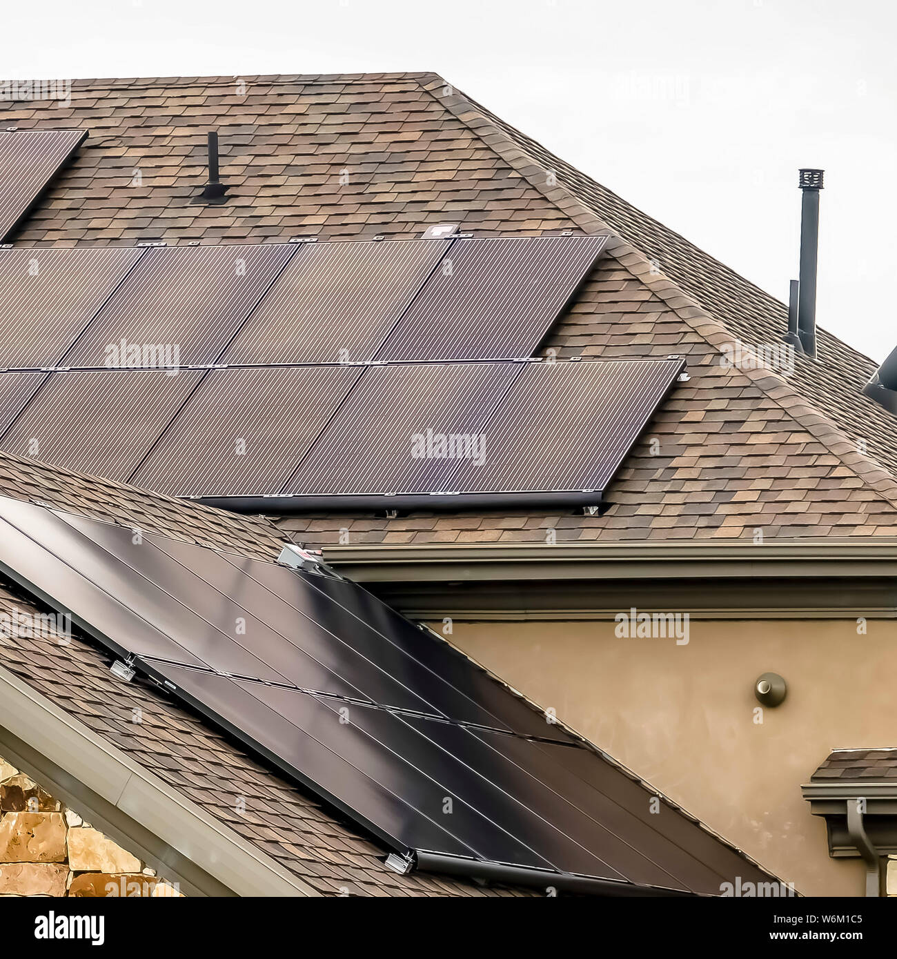 Square frame Solar panels on the dark pitched roof of a home with stone ...