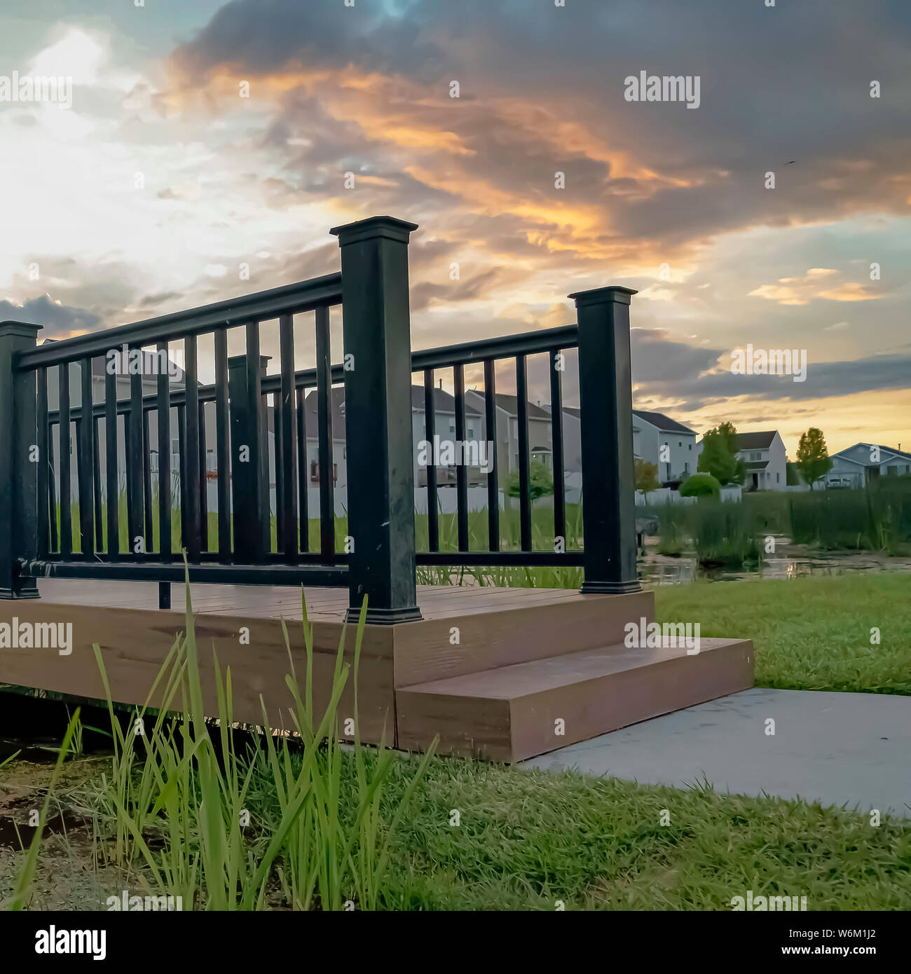 Square Bridge with wooden deck and black guardrail over a small and ...