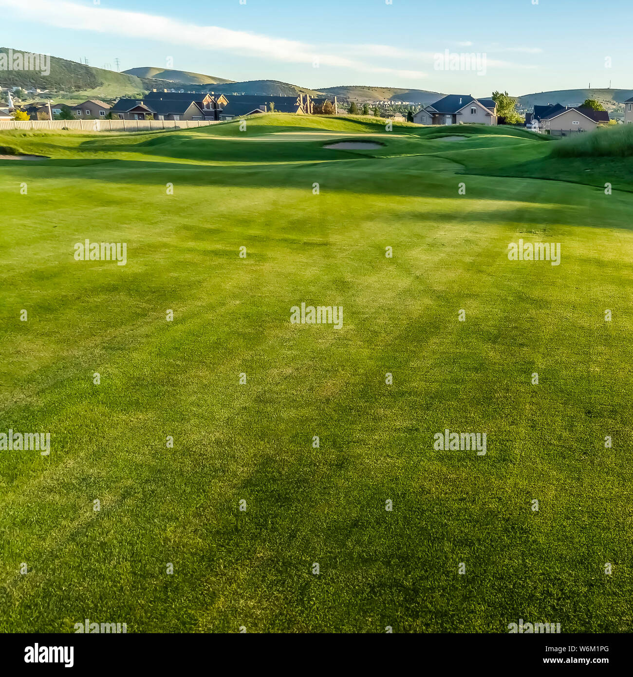 Square Fairway and bunkers of a golf course with homes and mountain in ...