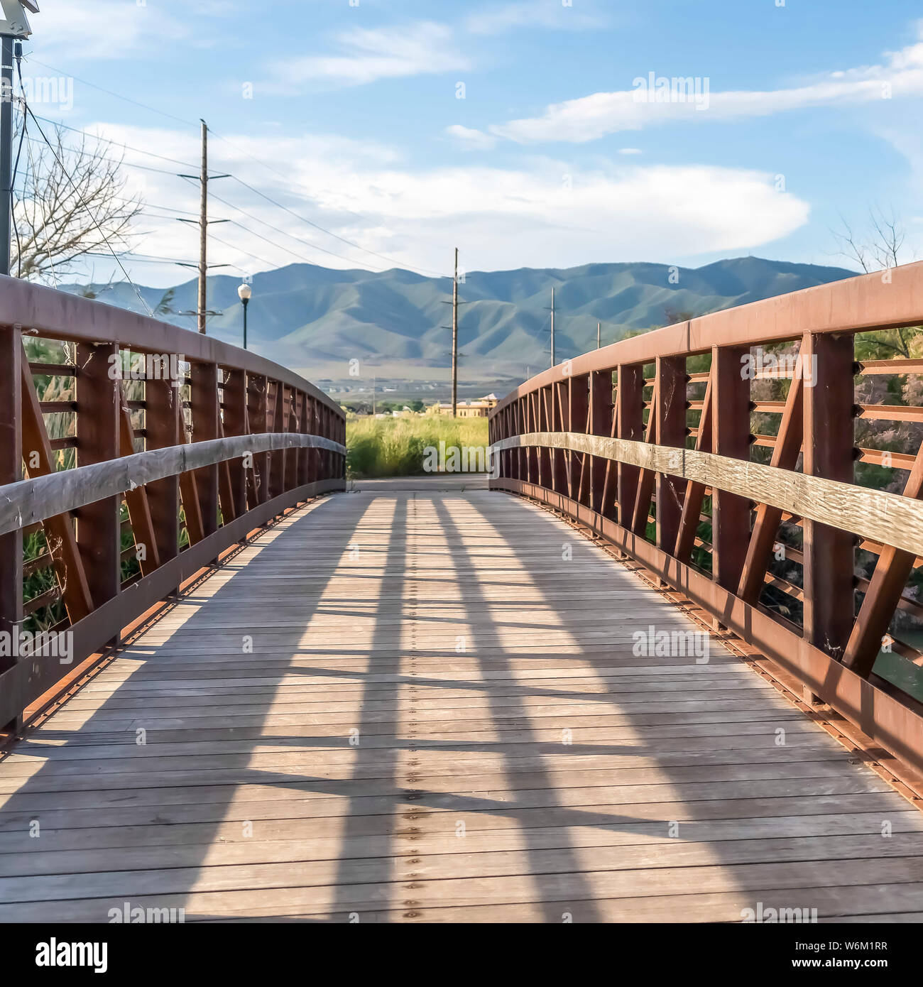 Square Wooden bridge with metal lattice guardrail over a lake with view ...