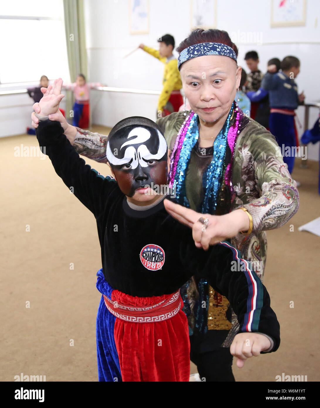 A pupil wearing a Chinese Beijing Opera or Peking Opera mask practises ...