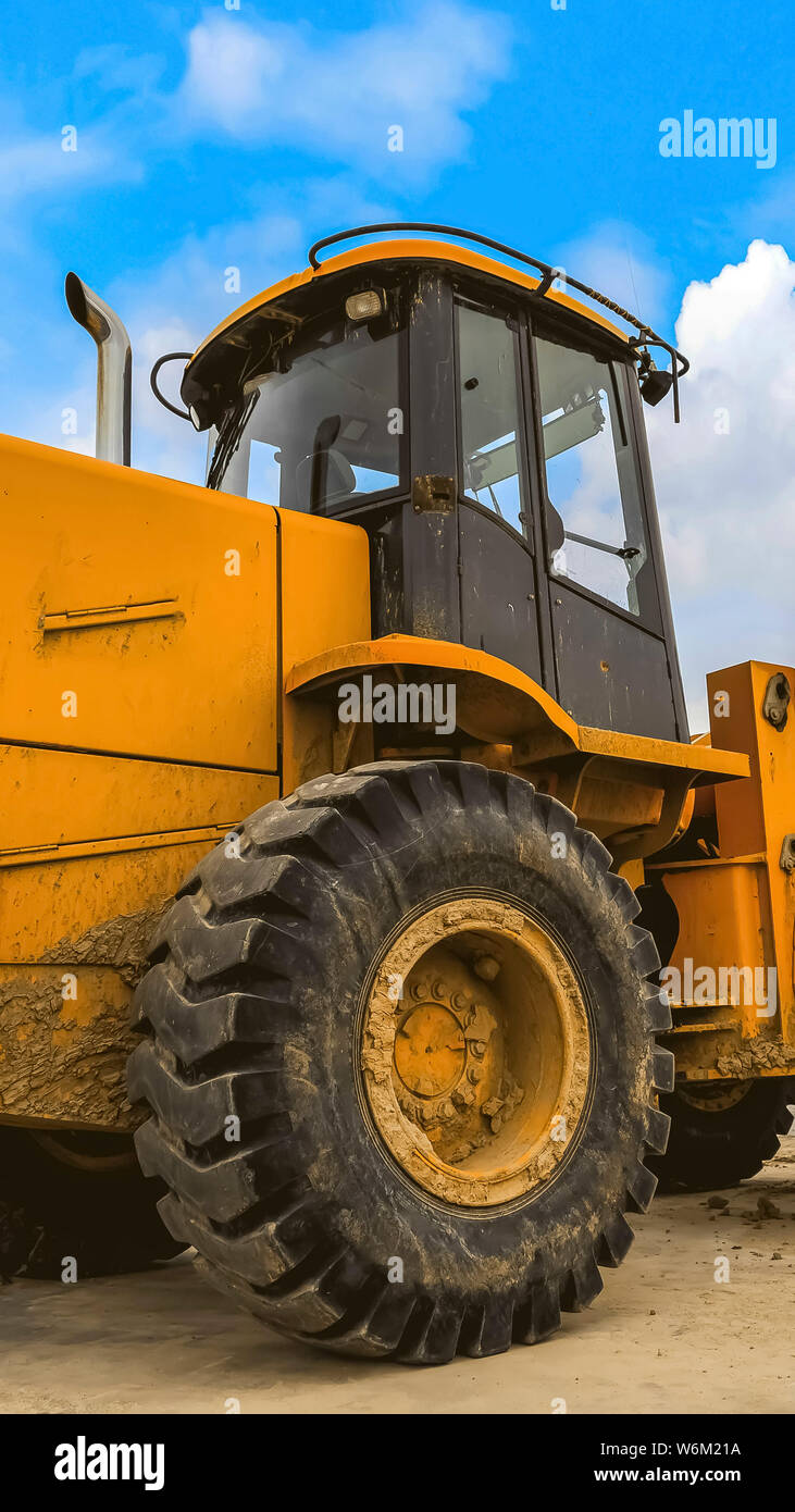 Vertical frame Close up of a dirty yellow loader with black rubber ...