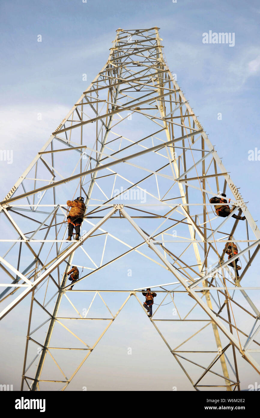 Chinese workers install a electricity pylon in freezing temperatures ...