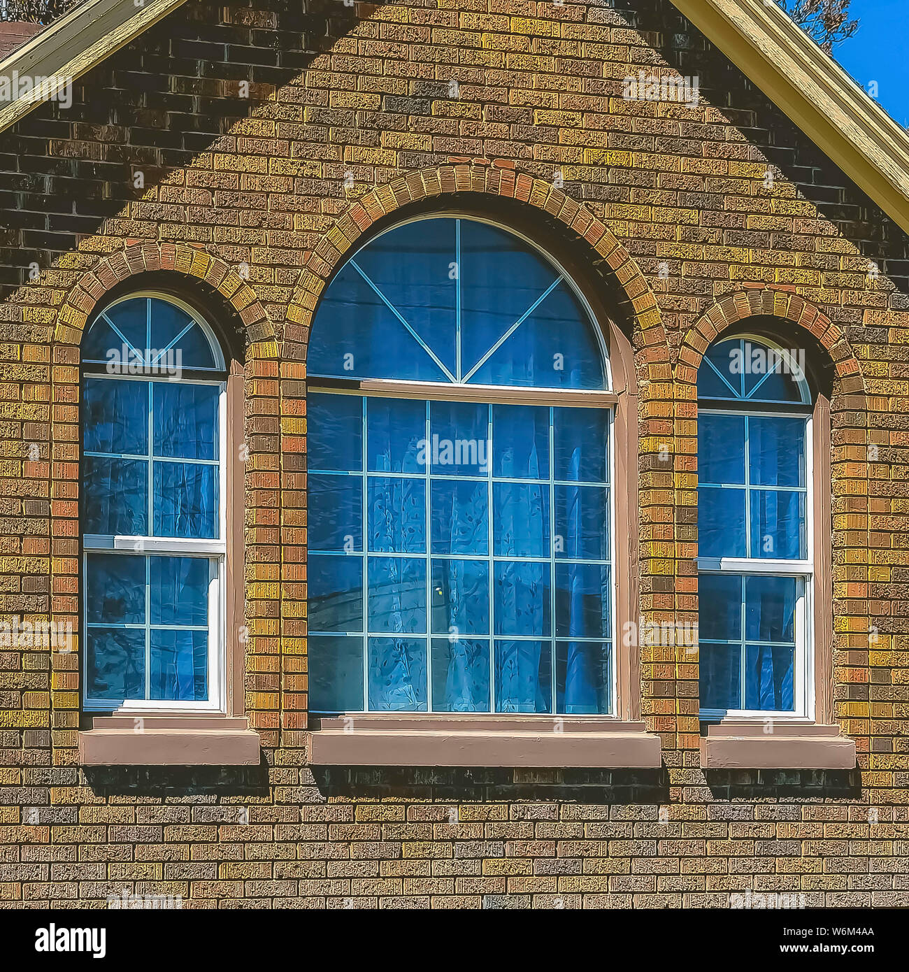 Square frame Home with brick wall and arched windows against blue sky ...