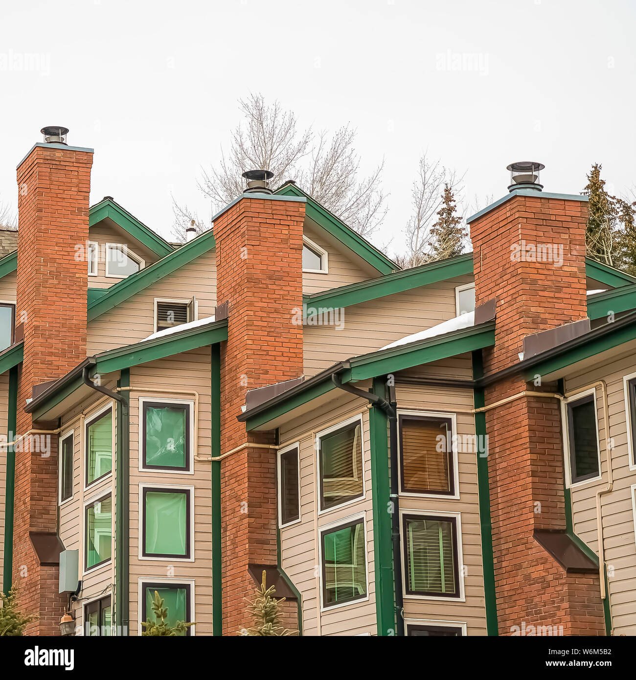 Square frame Homes with white wall sidings and red brick chimneys ...