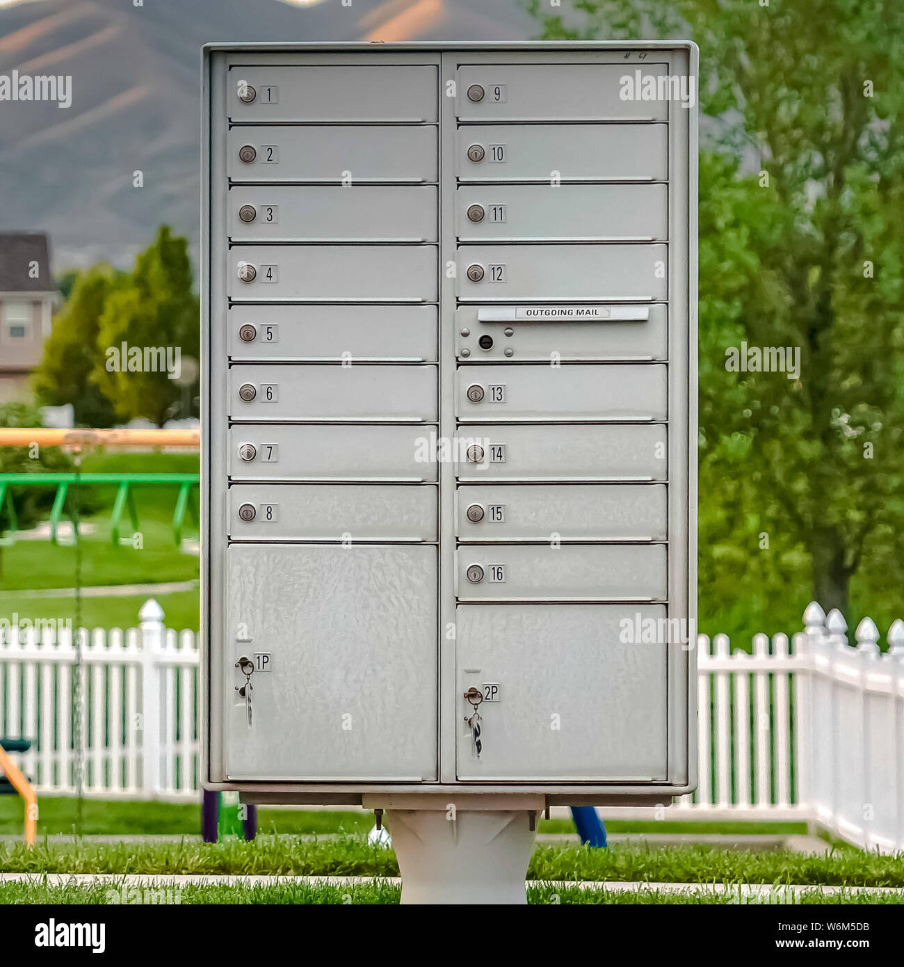 Square frame White metal cluster mailbox on the sidewalk in front of a ...