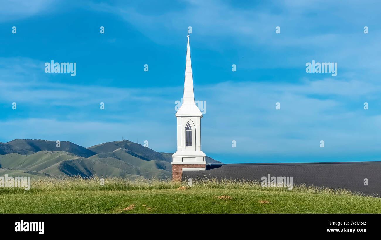 Panorama White steeple and rooftop of a church viewed from a grassy ...