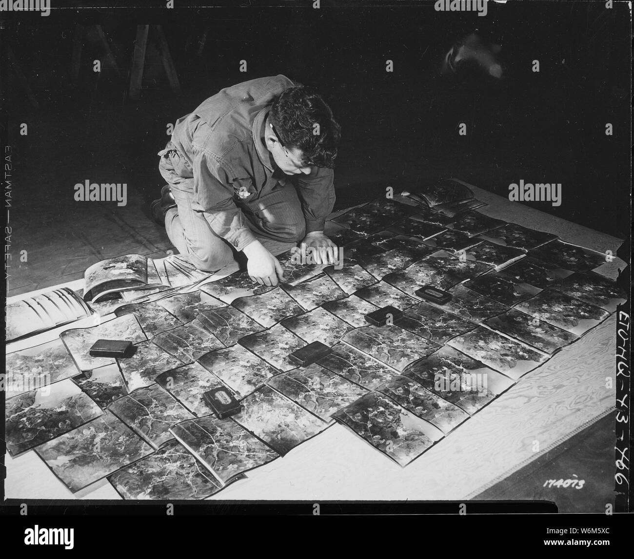 T/3 James Ellis, Ehrenfeld, Pennsylvania, laying out the photographs to ...