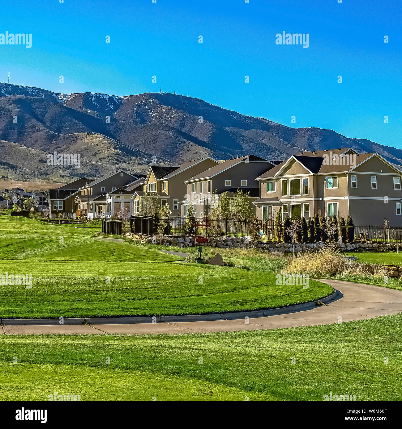 Square frame Narrow paved road curving through a grassy field in front ...