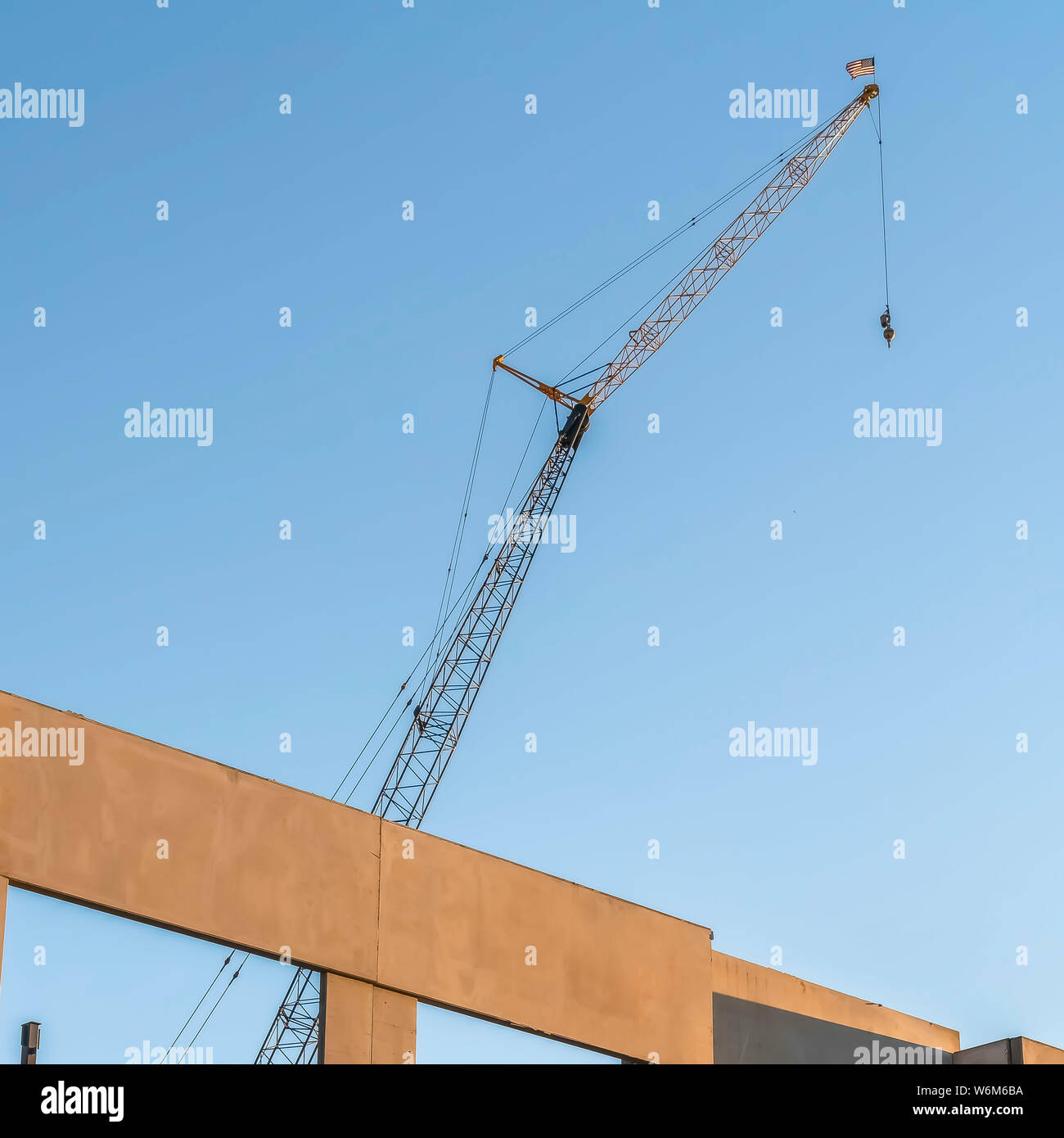 Square Building under construction with metal crane and blue sky ...