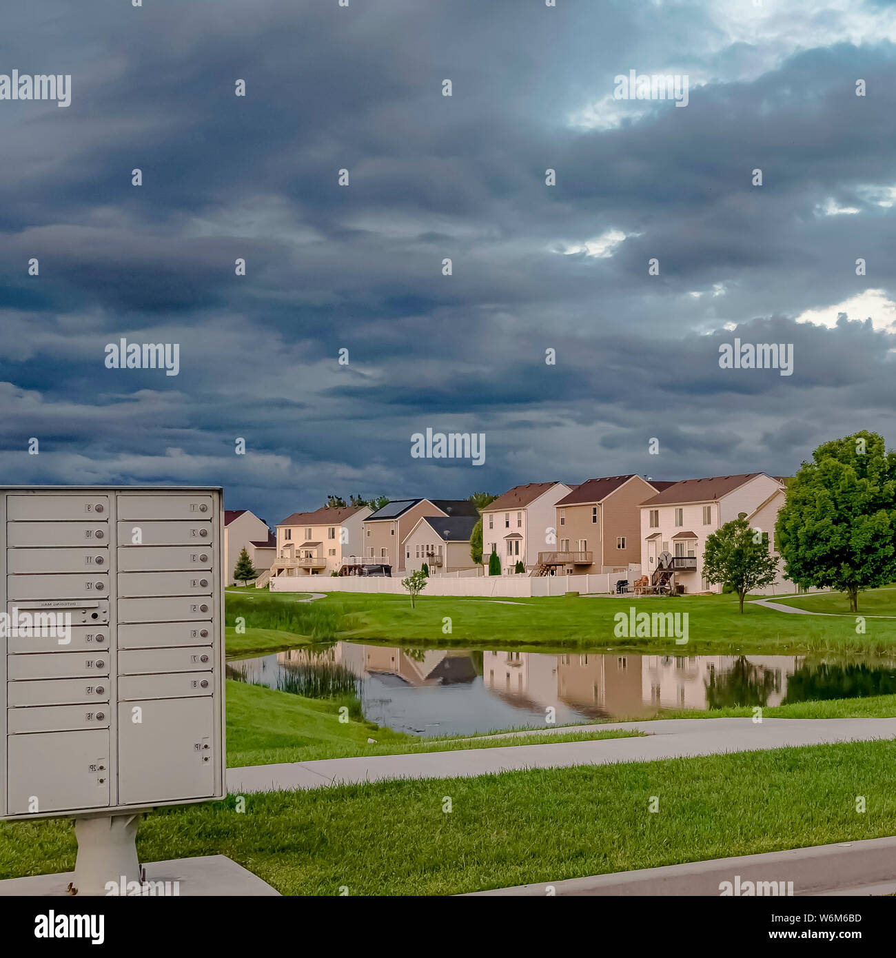 Square Sky filled with gray clouds over homes and pond amid a vast ...