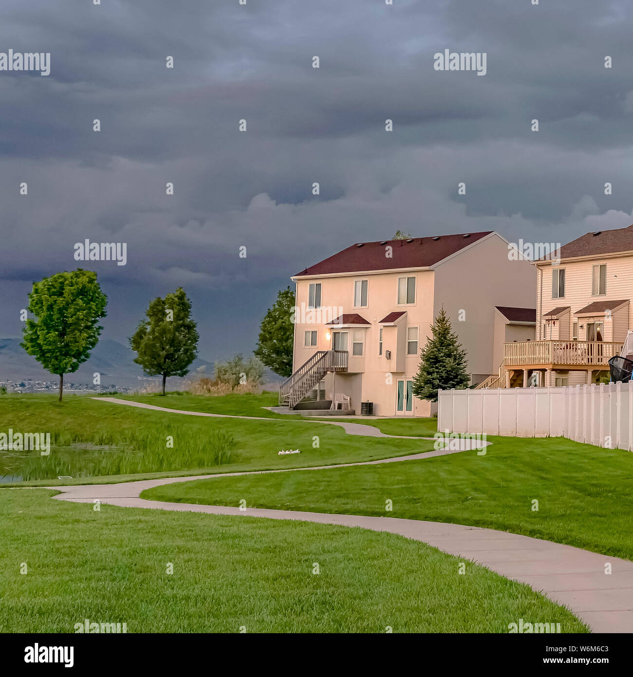 Square Home facade overlooking an expansive green field with a paved ...