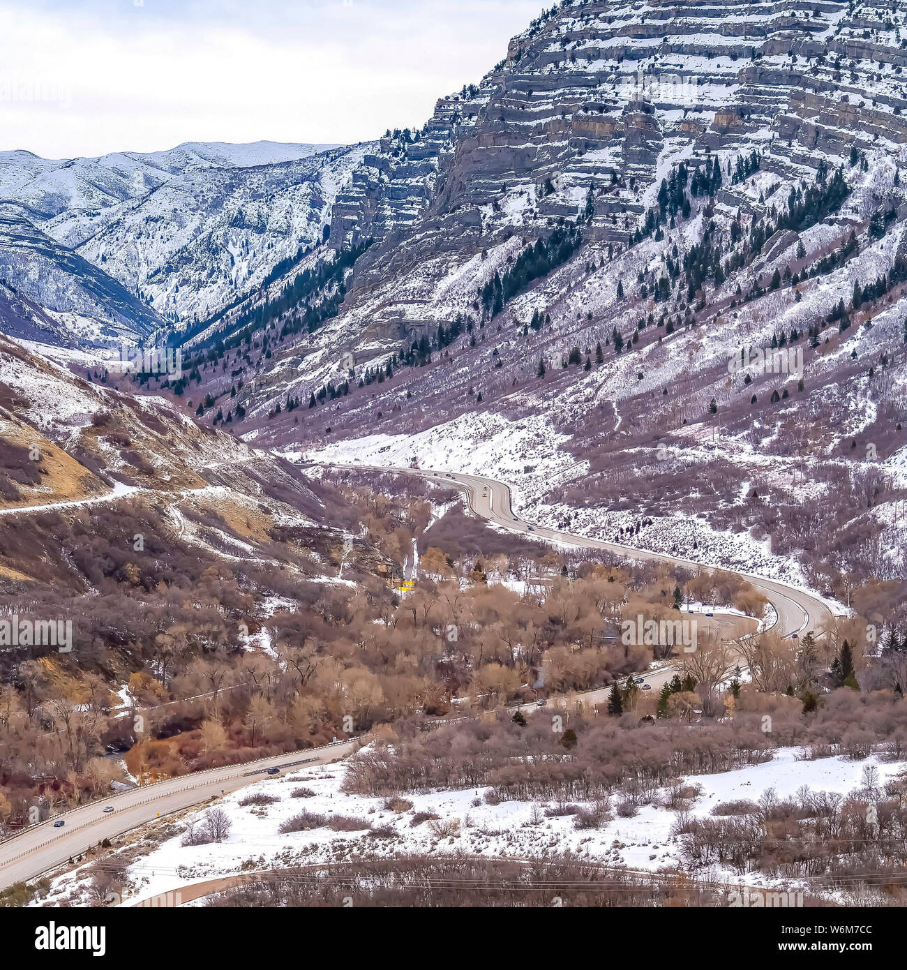 Square Road curving amid towering mountain with slopes covered in fresh ...