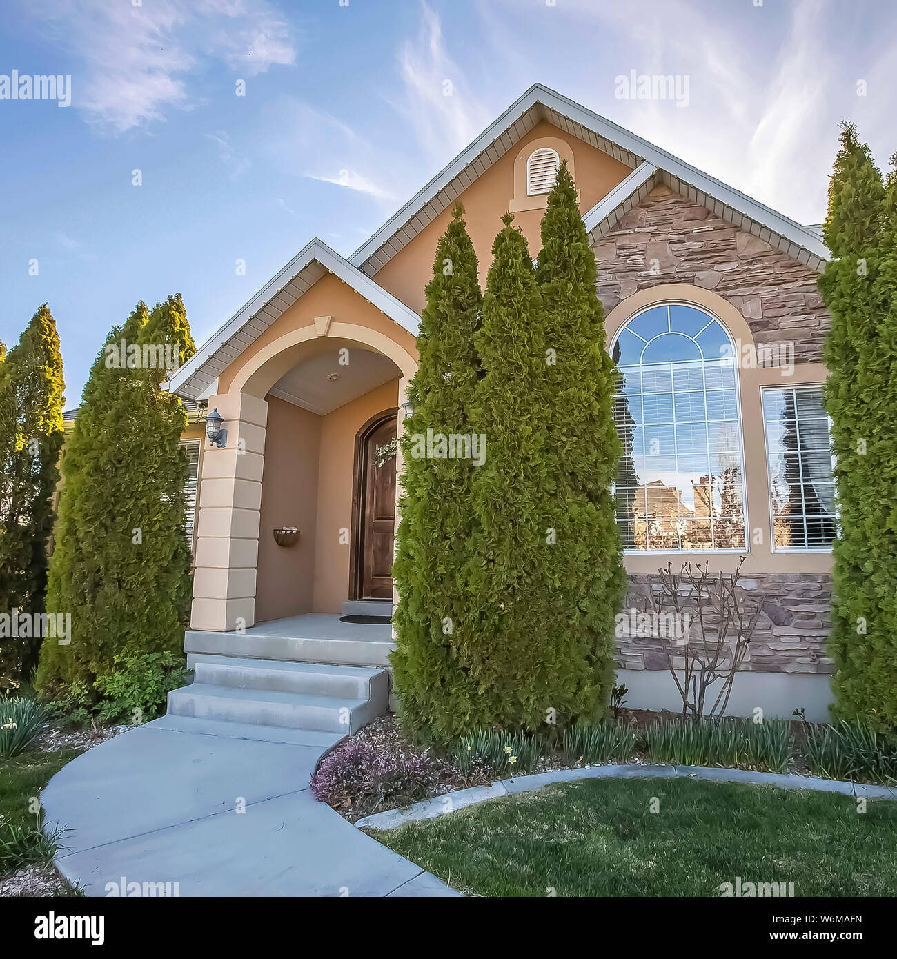 Square Home exterior with stone wall and pathway leading to the arched ...