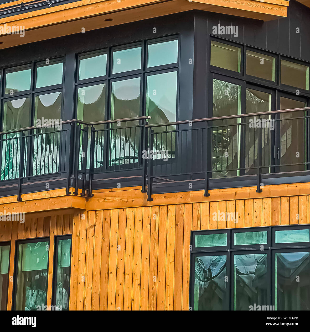 Square frame Exterior of a home with balcony shiny windows and gray and ...