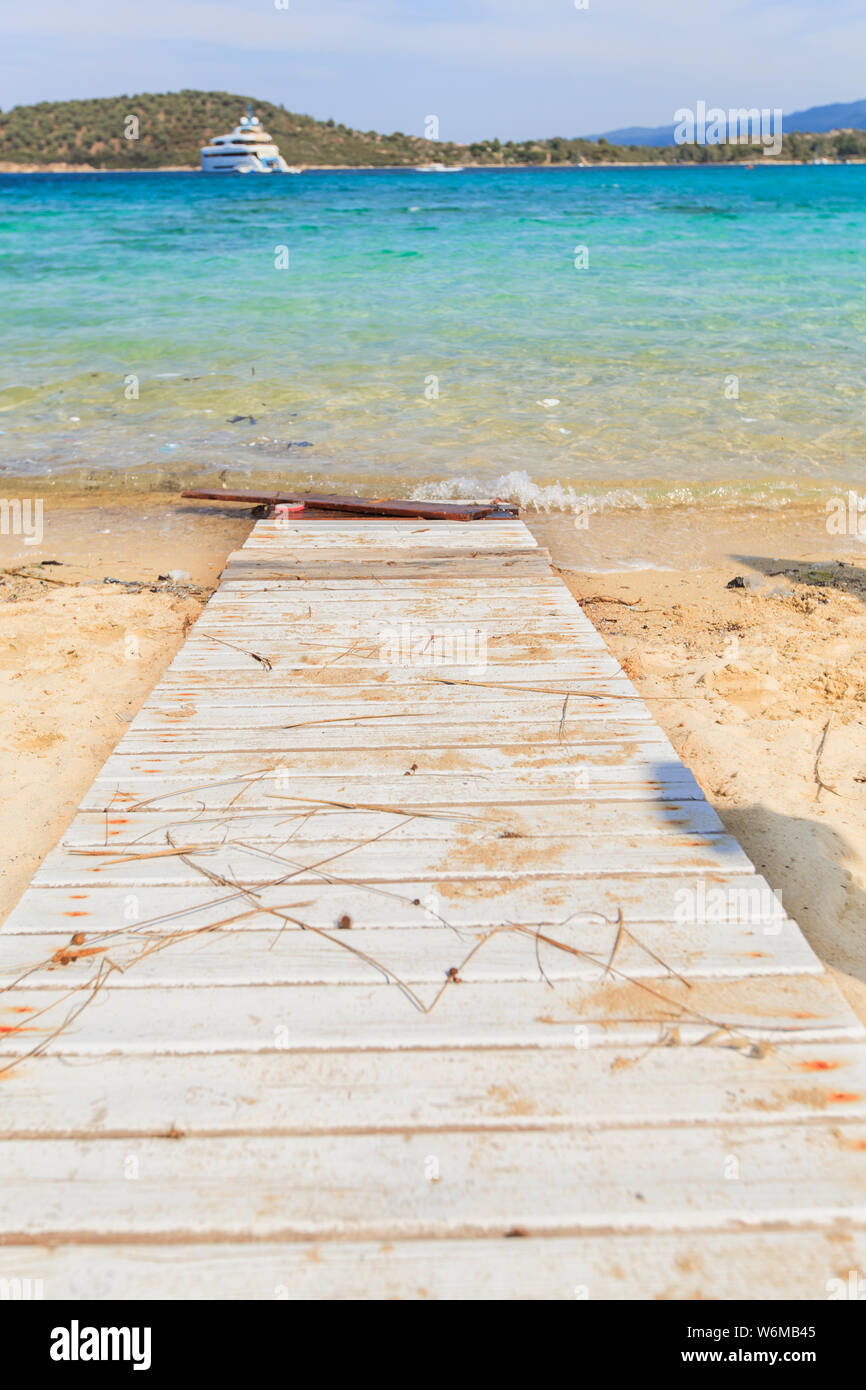Wooden path on sand beach. Summer seascape and turquoise sea water in ...